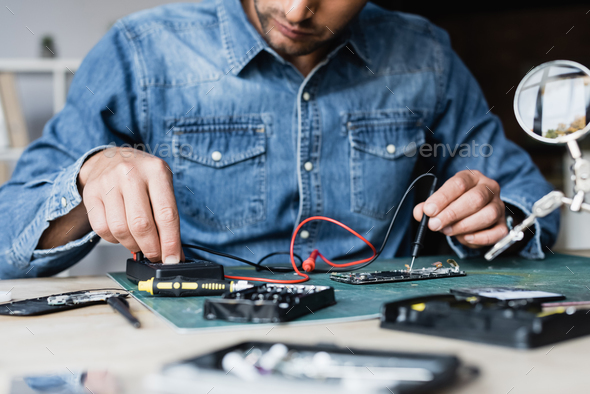 Cropped view of repairman using multimeter while holding sensor on ...