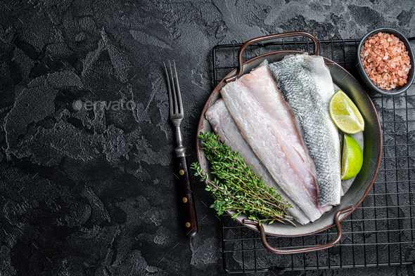 Raw Sea Bass fillet, Labrax fish with herbs and lime. Black background ...