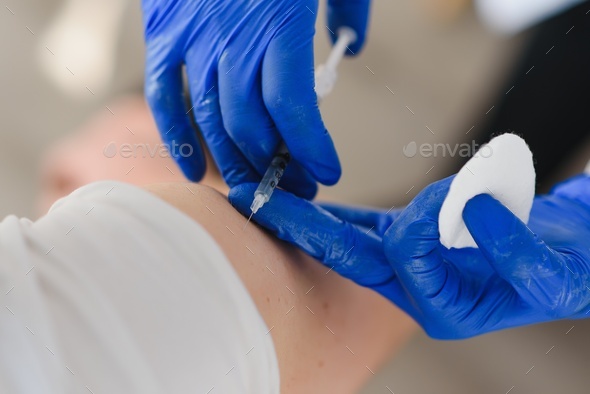 Female doctor making injecting using syringe to male patient in ...