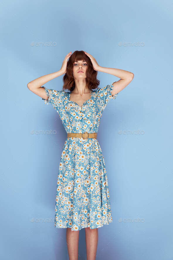 Woman in dress Keeps his hands on his head looking forward fashionable ...