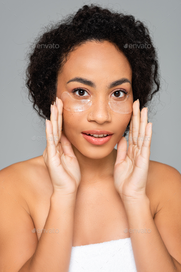 African american woman with perfect skin applying eye patches isolated ...