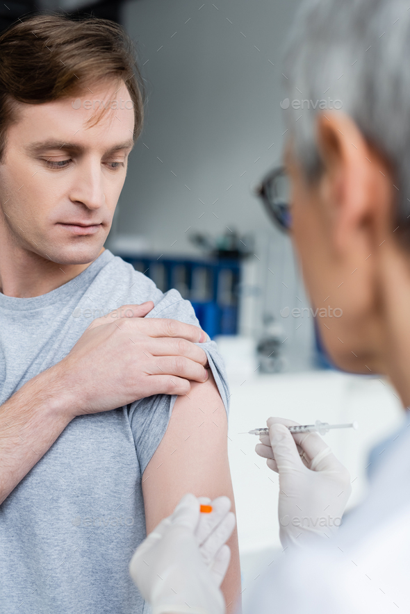 Patient standing near doctor with syringe on blurred foreground Stock ...