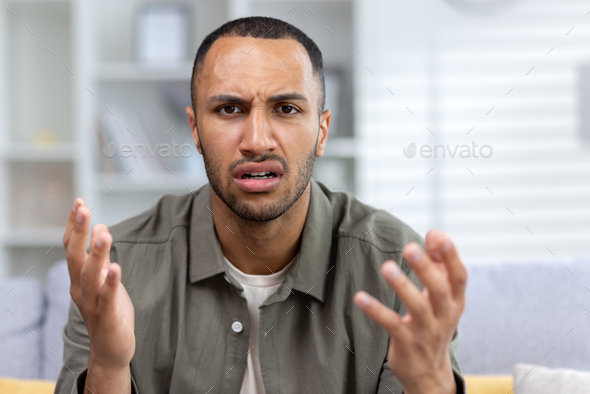 Close-up photo. Young upset and angry African American man sitting on ...