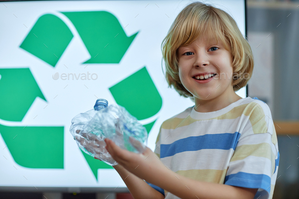 Smiling blonde boy holding plastic bottle in waste sorting and ...