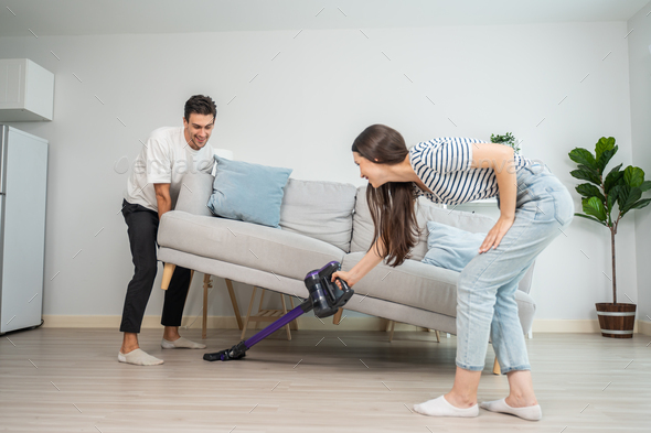 Caucasian young man and woman cleaning living room together at home ...