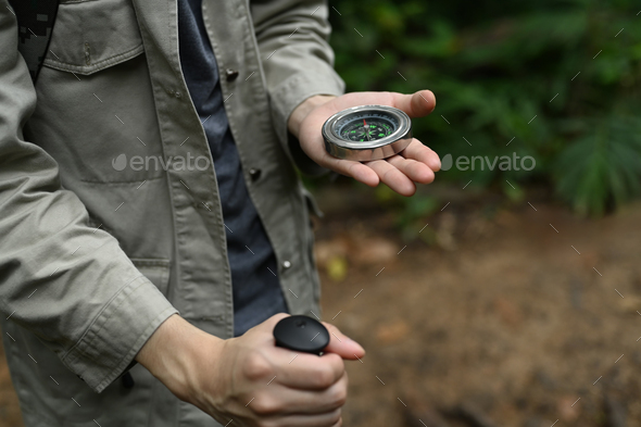 Male hiker using compass for directions in the forest, enjoying his ...
