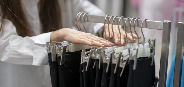 a close up hand holding a clothes hanger and choosing the new outfit in ...
