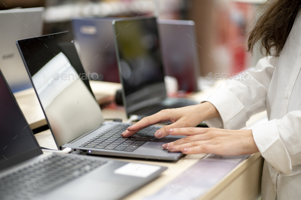 a client in a retail shop choosing a new laptop for studying and ...