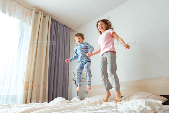 Children jump on the bed.The boy and the girl are having fun at home ...