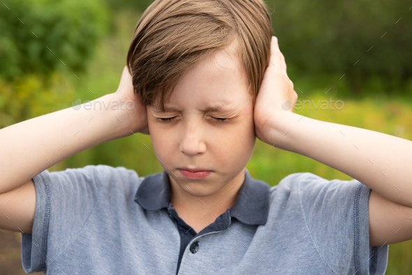 Little Caucasian boy closing ears with his hands. Childhood traumatic ...