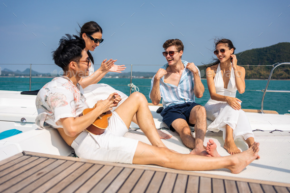 Group of diverse friend sit on deck of yacht while yachting together ...
