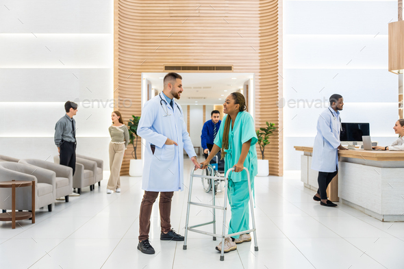 Caucasian doctors support patient walk through the hallway in hospital ...