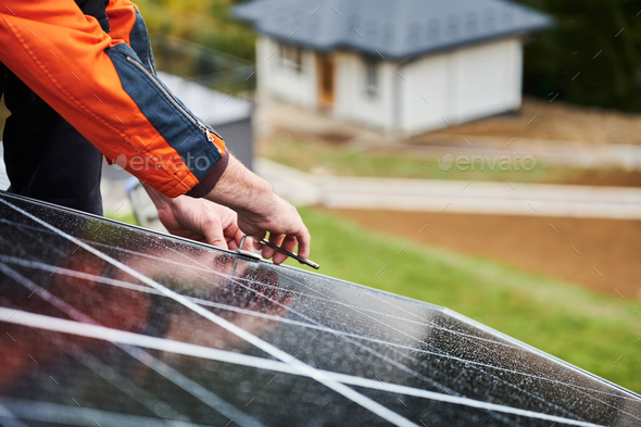 Man technician mounting photovoltaic solar panels on roof of house with ...