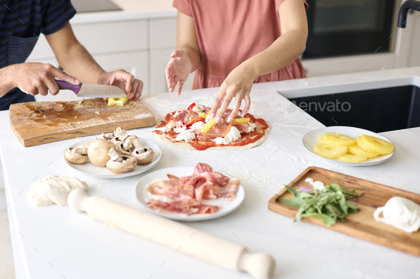 Close Up Of Couple At Home Putting Toppings On Pizza In Kitchen ...