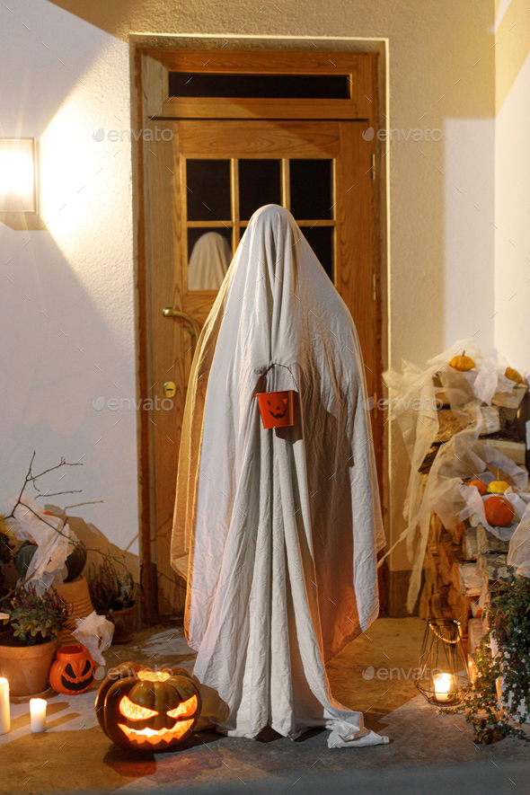 Scary ghost with glowing Jack o lantern at doors in spooky atmospheric ...