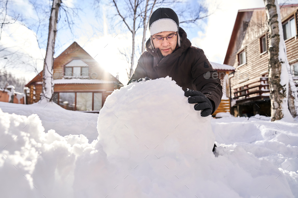 A family builds a snowman out of snow in the yard in winter. Stock ...