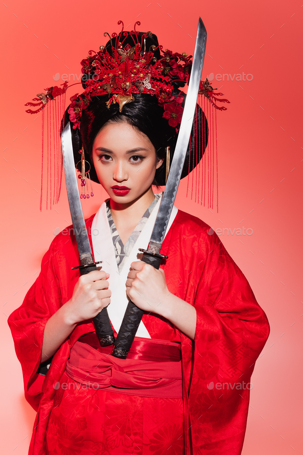 Japanese woman in traditional costume holding swords on red background ...
