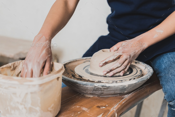 partial view of young african american woman modeling wet clay on wheel ...