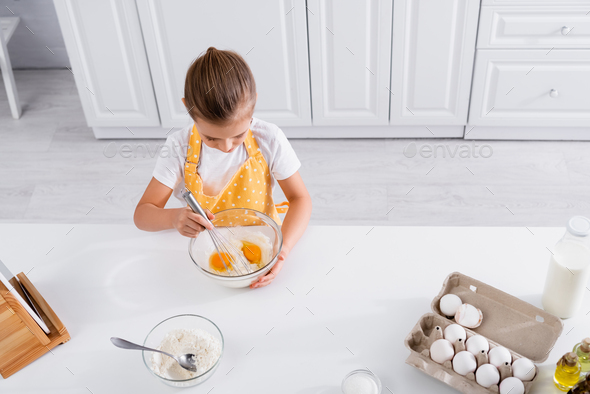 Overhead view of kid in apron mixing eggs in bowl in kitchen Stock ...