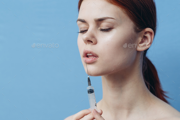 women give injections in the face on a blue background syringe vaccine ...