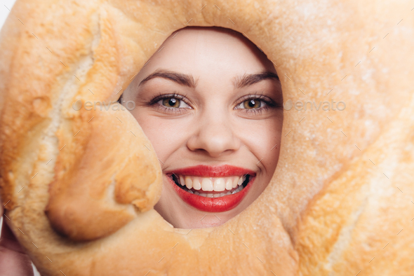 happy woman with round loaf of bread in front of face bright makeup ...