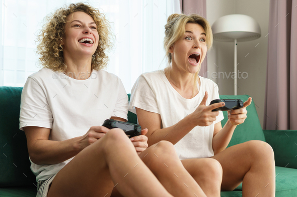 Two beautiful girls playing video game console in a living room Stock ...