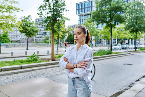 Serious confident teenage girl looking forward, outdoor on city street ...