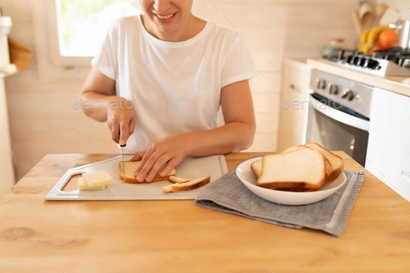 a woman sits in the kitchen cutting off crusts of bread Stock Photo by ...