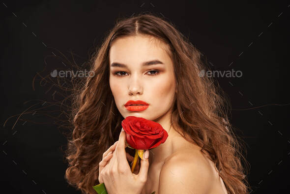 woman with a red rose on a dark background long hair makeup red lips ...
