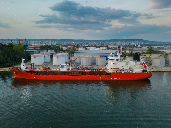 Tanker ship refueling at an oil terminal with storage silo's in the ...