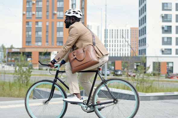 Side view of African American male entrepreneur riding to work by ...