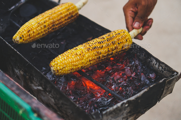 Grilled corn on the cob burning on the hot charcoal grill. Grilled and ...