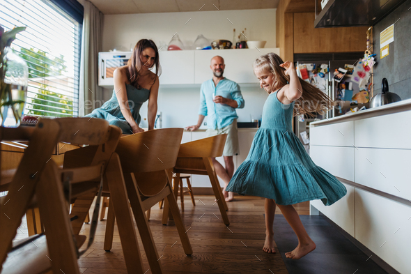 Little girl dancing in the kitchen, while parents watching her. Stock ...