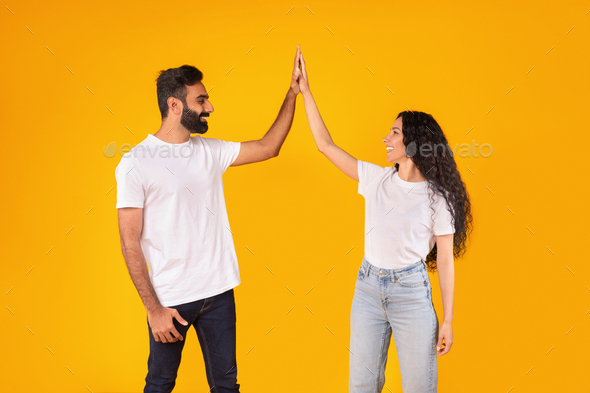Cheerful Arab Young Couple Giving High Five Over Yellow Background ...