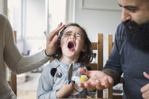 Mother and step-father trying to calm dawn crying daughter at table ...