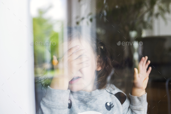 Little girl standing behind window Stock Photo by astrakanimages ...