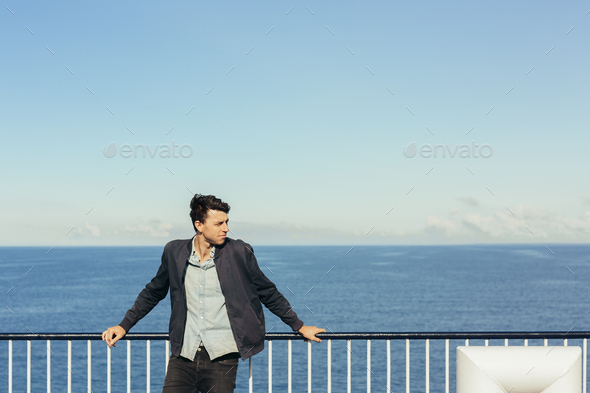 Man leaning on railing on ship deck Stock Photo by astrakanimages ...