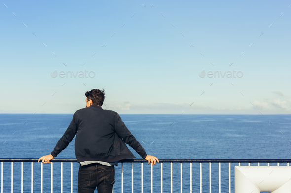Man leaning on railing on ship deck Stock Photo by astrakanimages ...