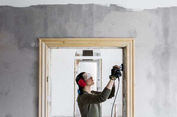 Woman polishing door frame during renovation Stock Photo by astrakanimages