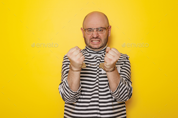 Man wearing prison uniform and handcuffs on yellow background Stock ...