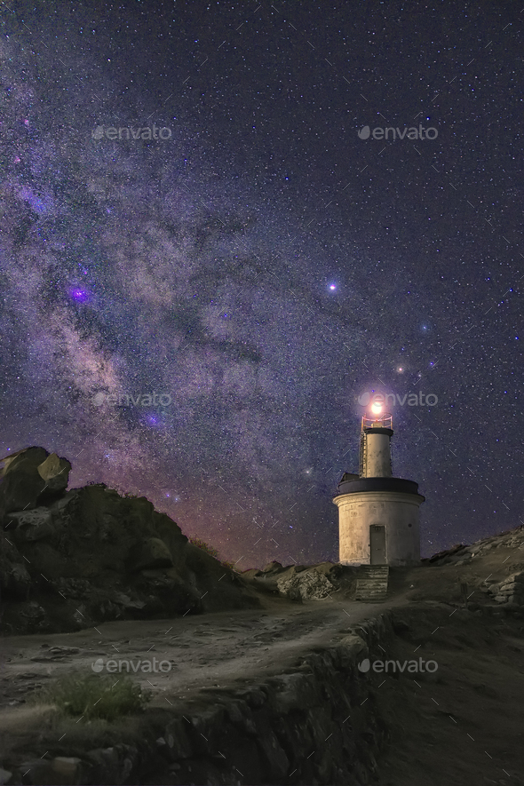 Vertical shot of an illuminated lighthouse placed on a shore in the ...