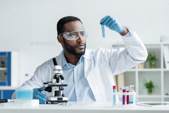 African american scientist in latex gloves and safety goggles holding ...
