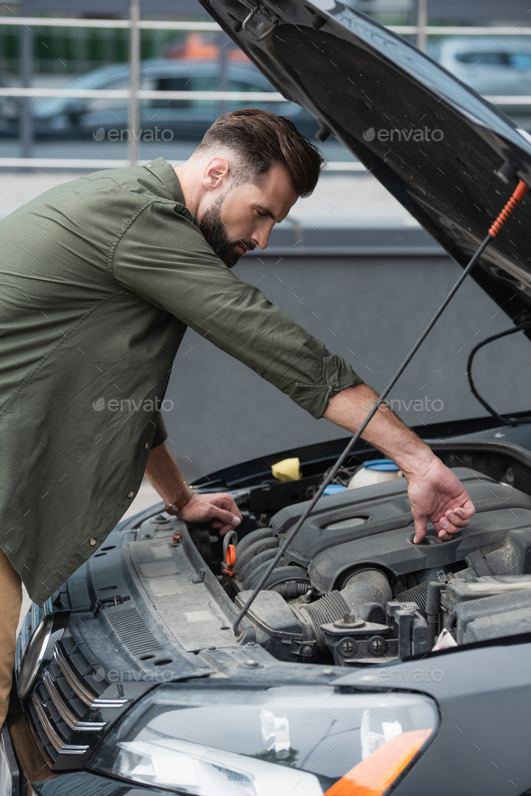 Side view of man opening cap of motor in car outdoors Stock Photo by ...
