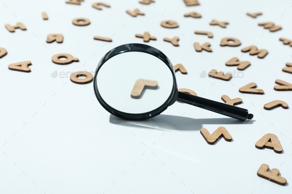 Magnifying glass and wooden letters on white background, space for text ...