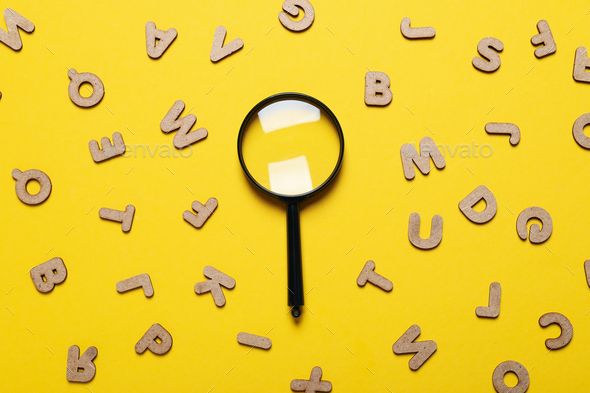 Magnifying glass and wooden letters on yellow background, top view ...