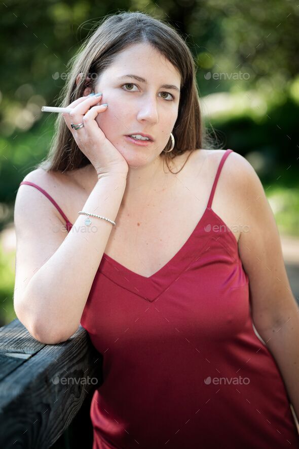 Brunette girl in a blush dress with her head in her hands, leaning on a ...