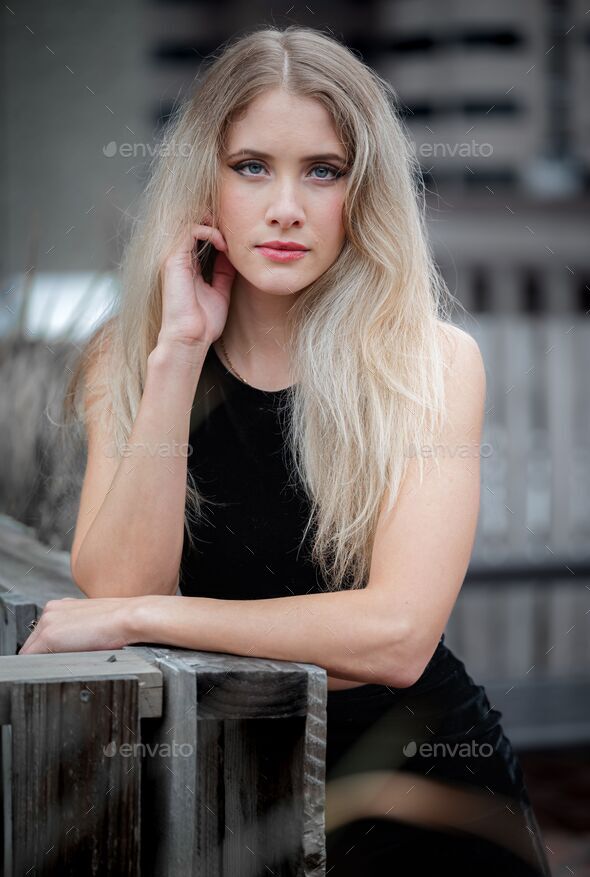 Elegant blonde girl in a black dress with an exposed midriff posing in ...