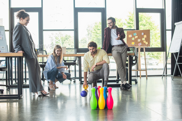 Positive interracial business people playing bowling in office Stock ...