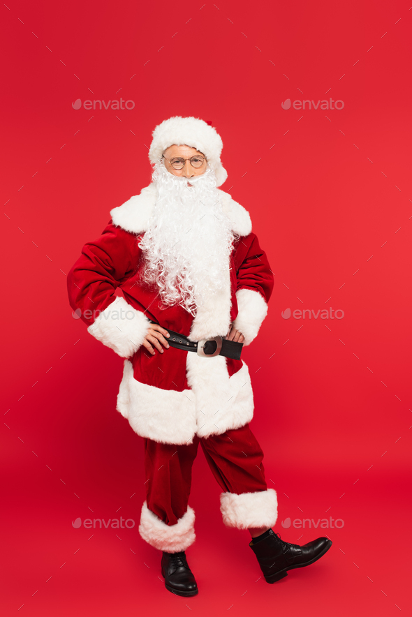 Santa claus in costume holding hands on hips on red background Stock ...
