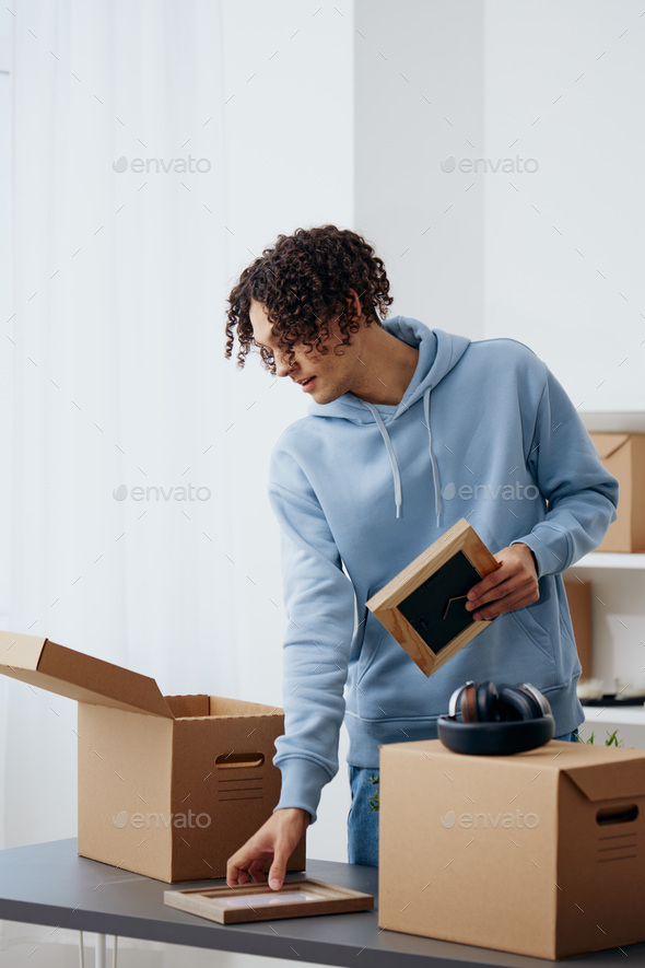 portrait of a man unpacking things from boxes in the room sorting ...